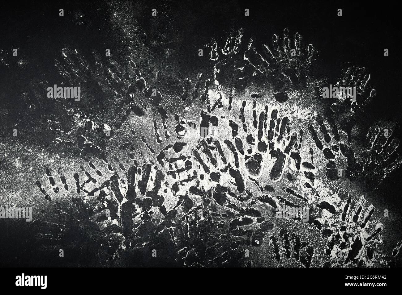 Random pattern of palm prints in white flour on a black slate ...