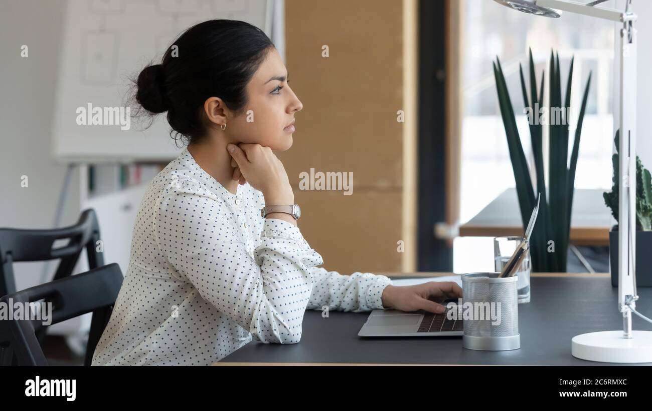 Pensive indian female employee look in distance thinking Stock Photo ...