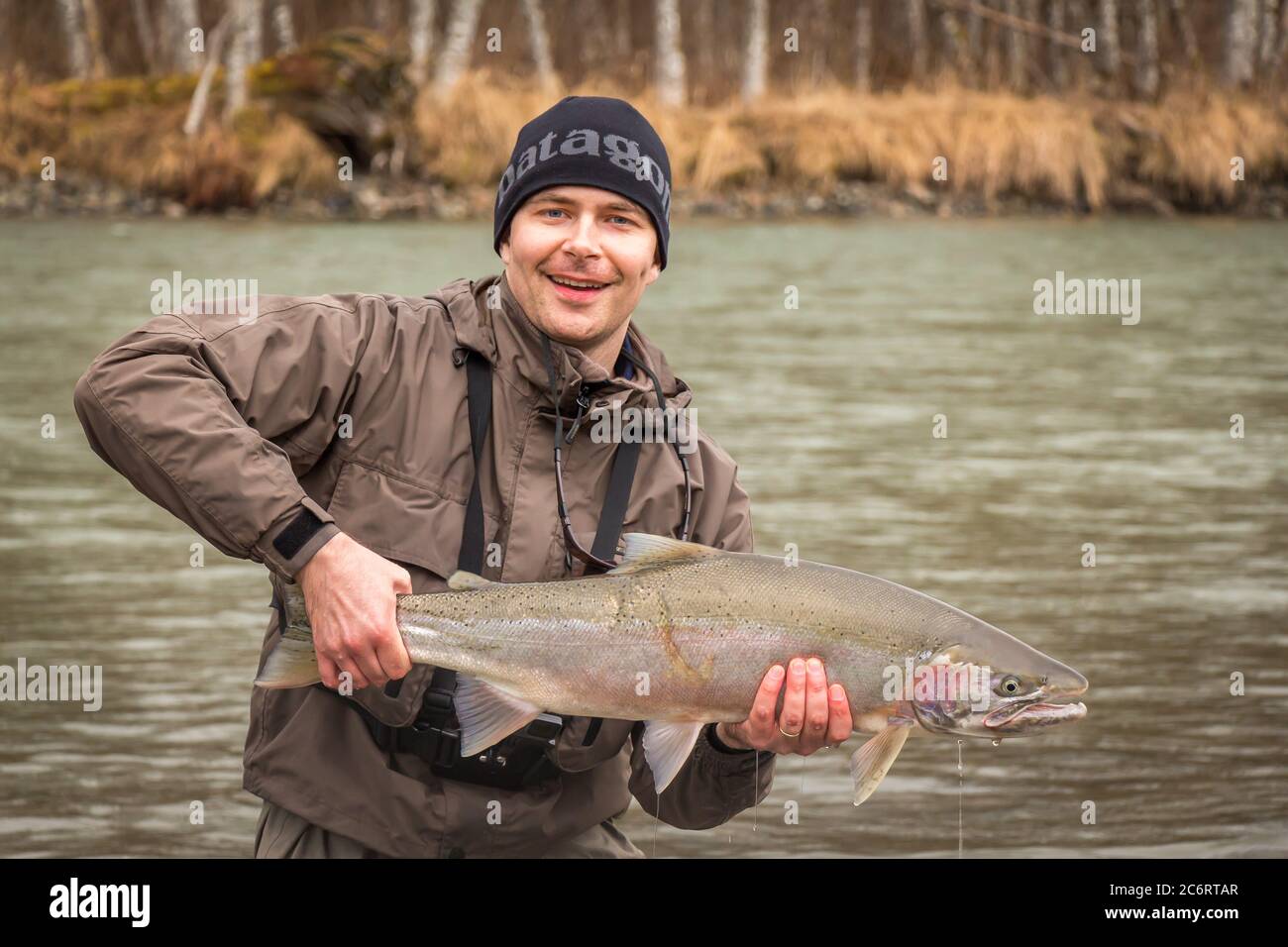 A happy fisherman holding up a fresh steelhead, rainbow trout, with a ...