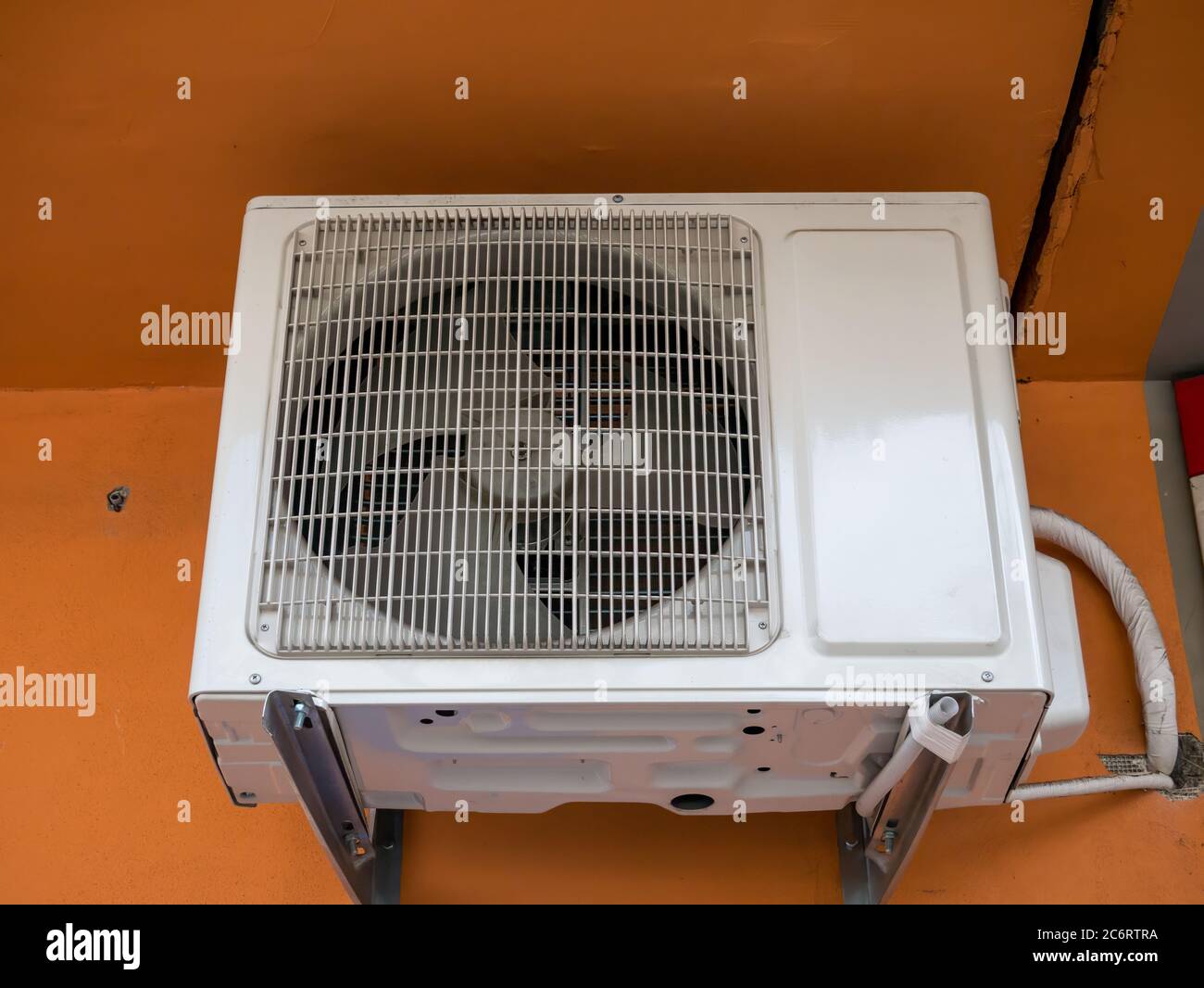 Air conditioner compressor unit on orange wall Stock Photo - Alamy