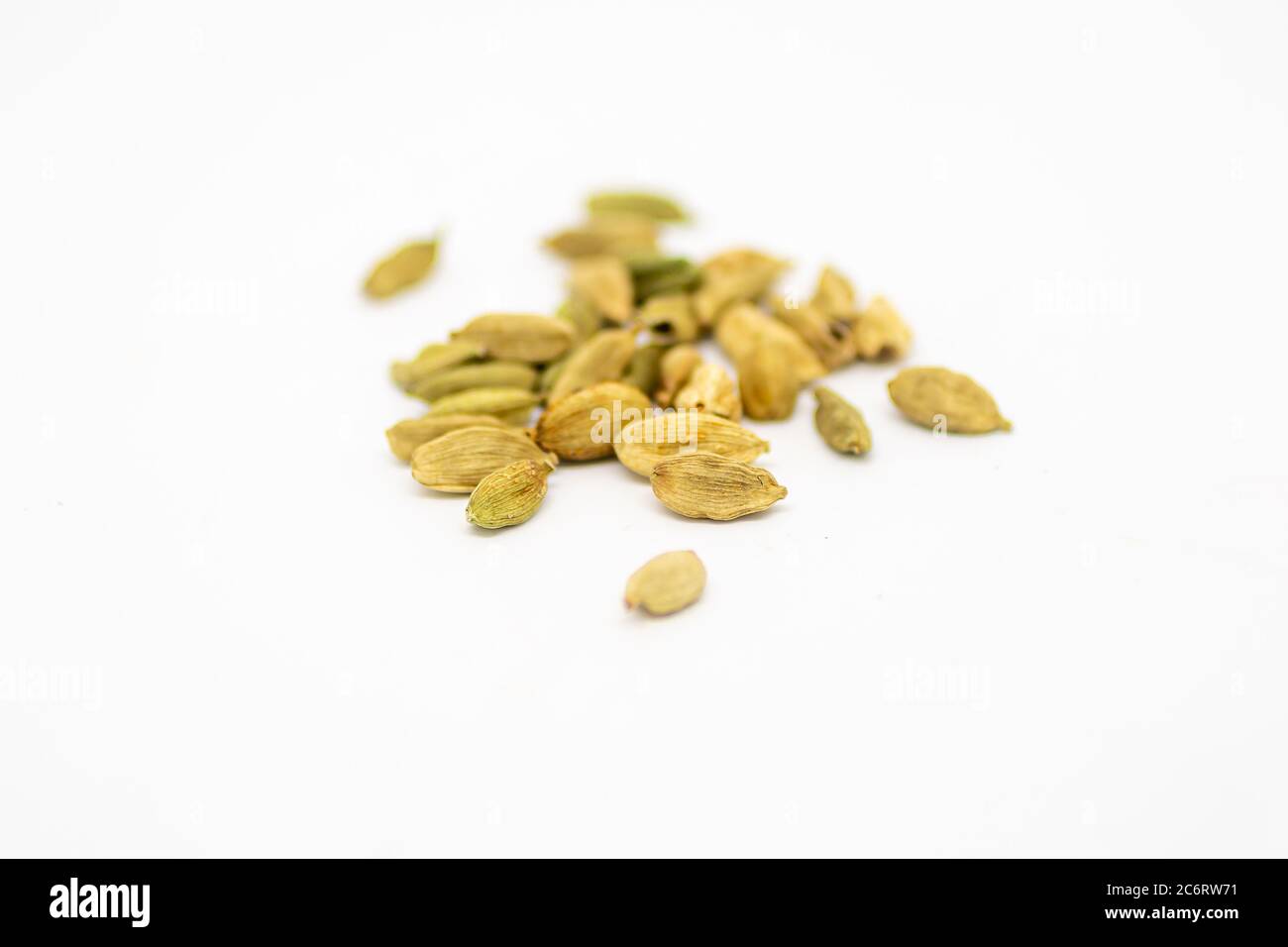 Whole cardamom pods with a shallow depth of field, against a white ...