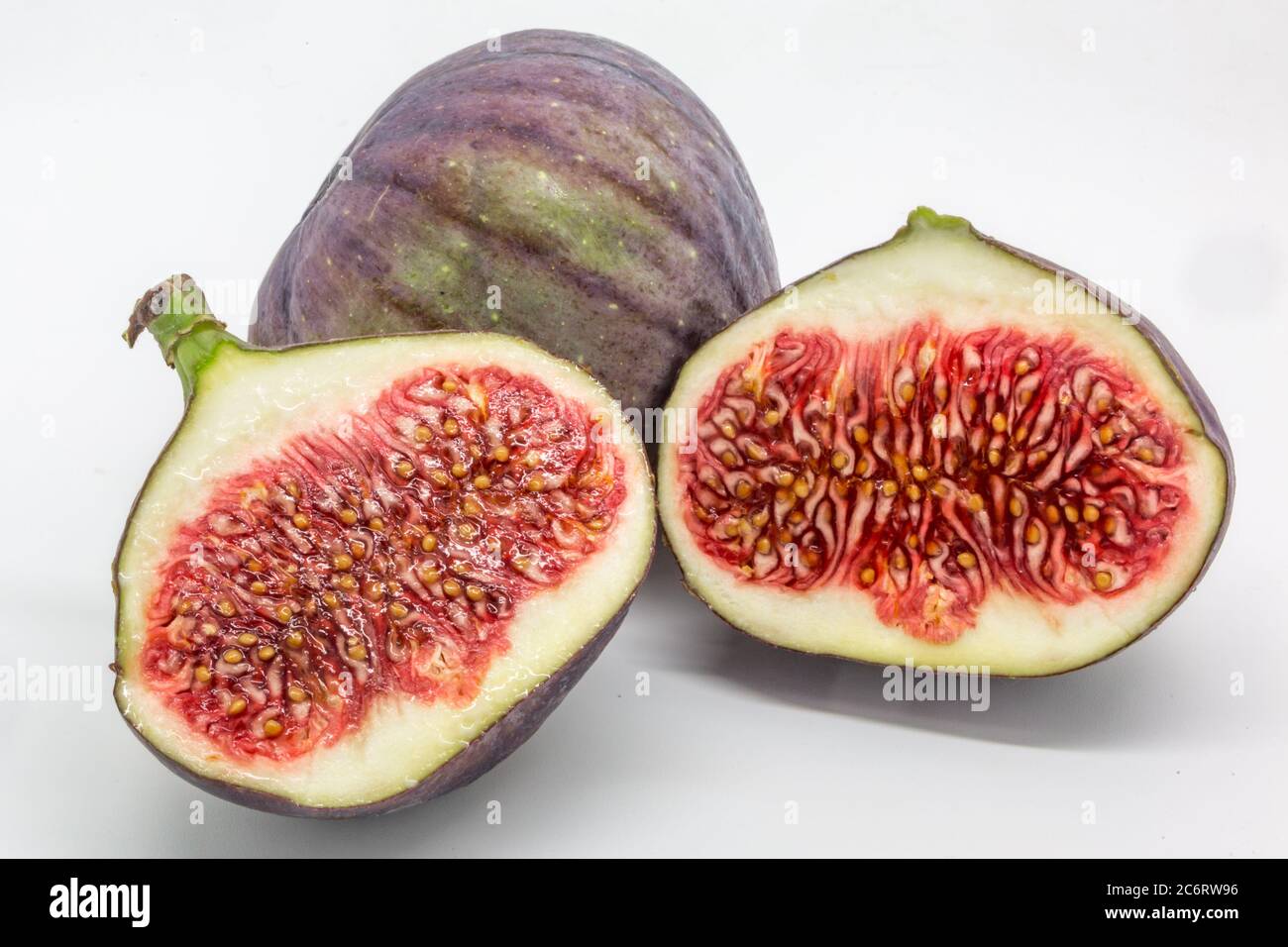 Fresh figs against a white background, with one cut to show the seeds ...