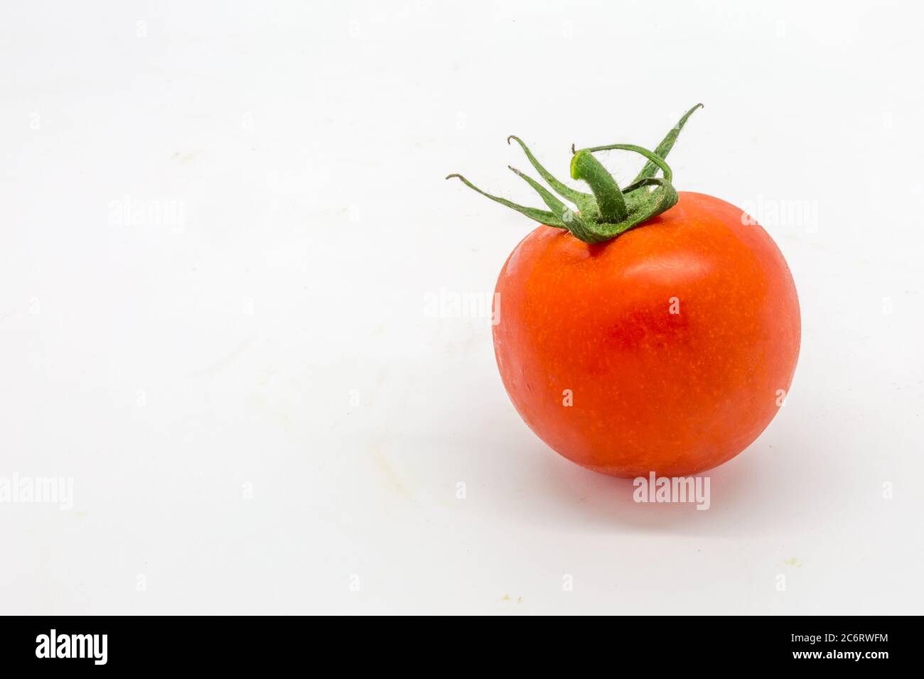 A single red tomato against a white background Stock Photo - Alamy