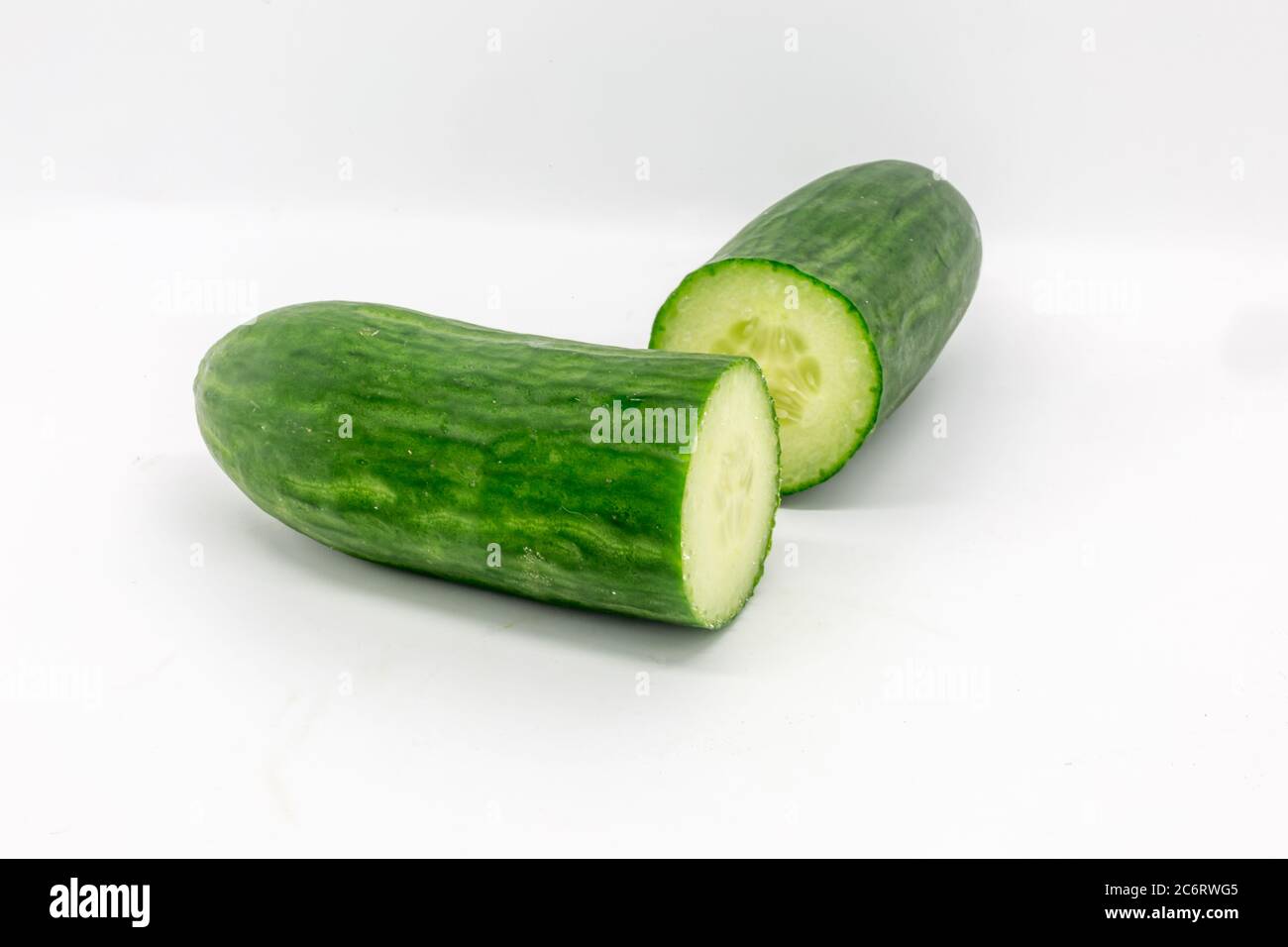 A cucumber cut in half, against a white background Stock Photo - Alamy