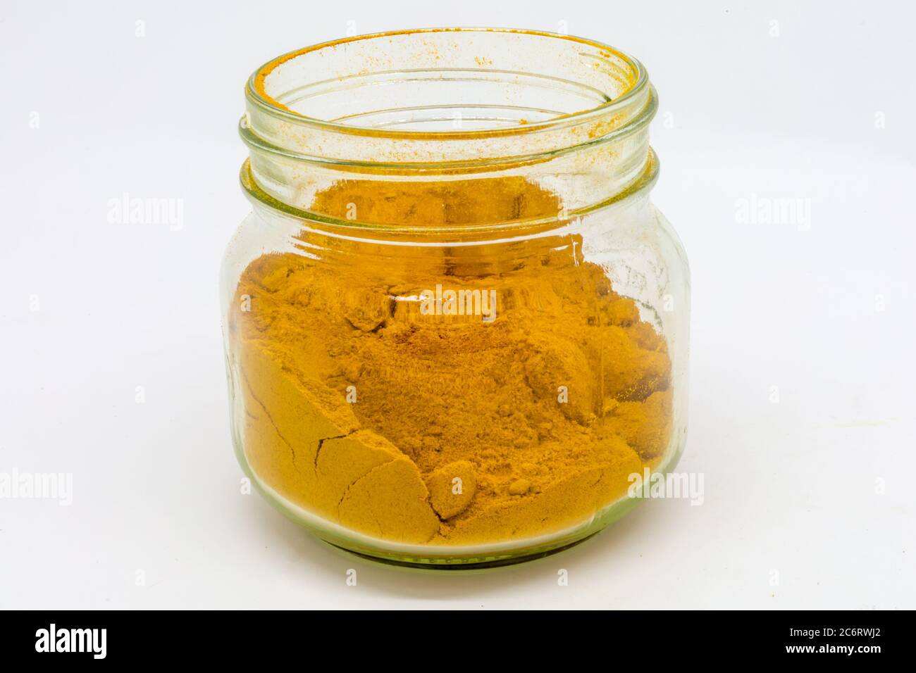 A jar of ground turmeric against a white background Stock Photo - Alamy