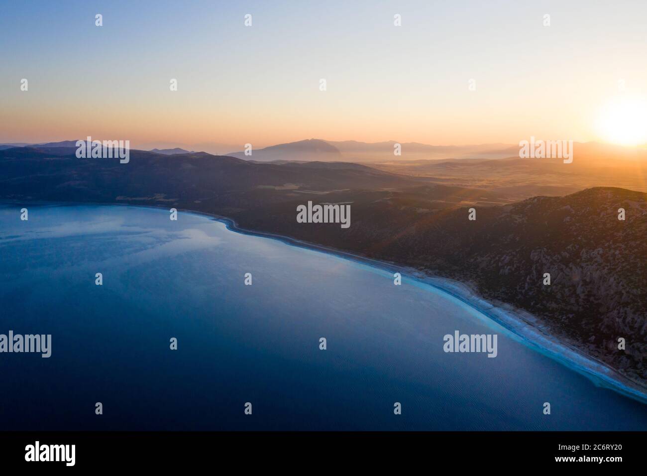 An aerial view of a lake with sunrise and silhouette hill background ...