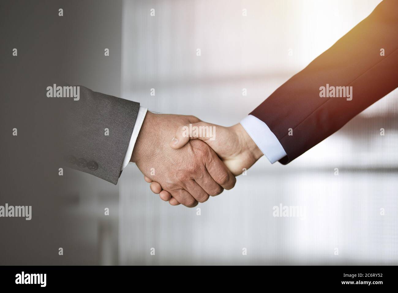 Business people standing and shaking hands in sunny office, close-up ...