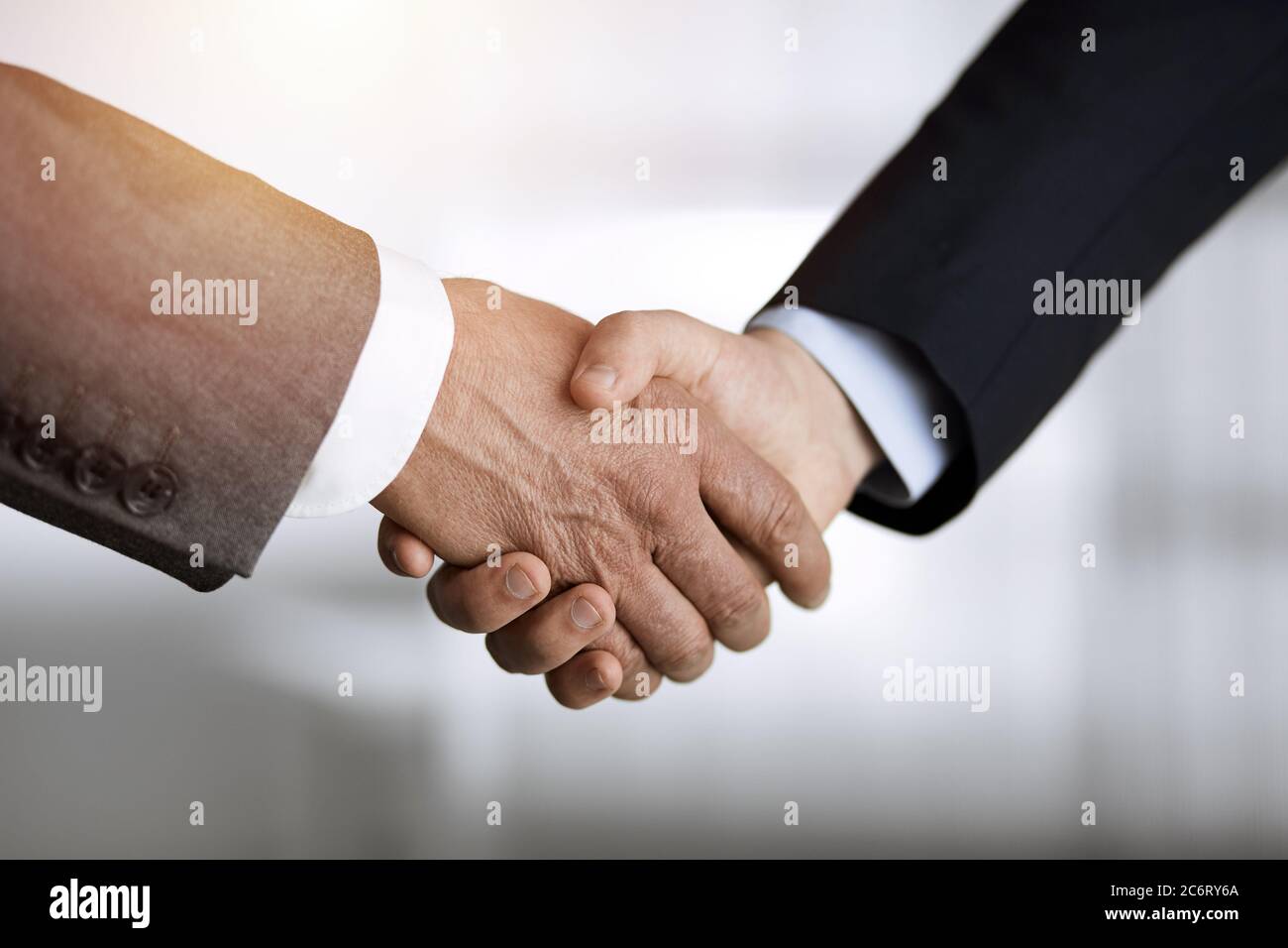 Business people standing and shaking hands in sunny office, close-up ...