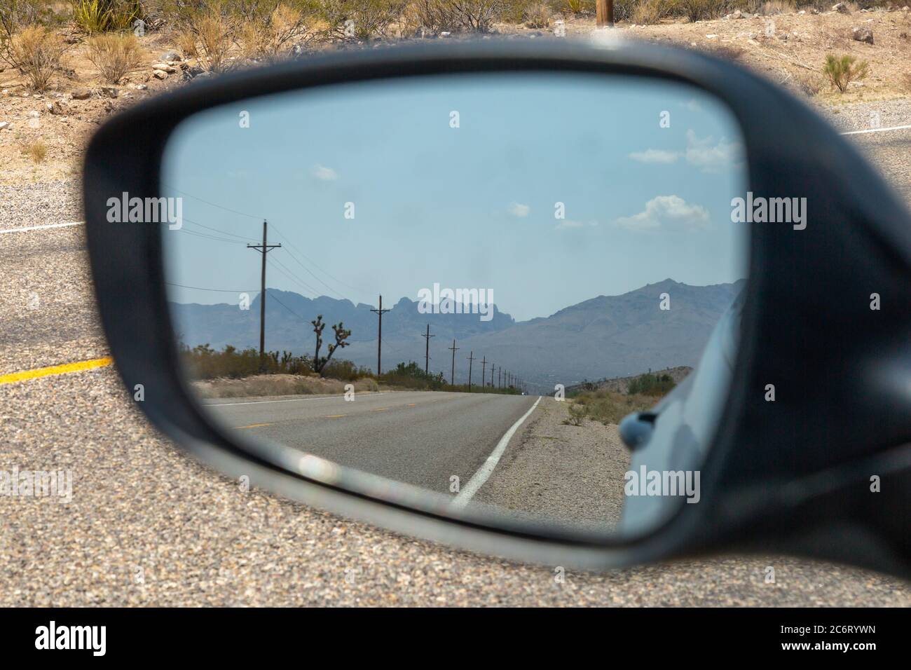 Looking into the rear view mirror of a car, with telegraph poles ...