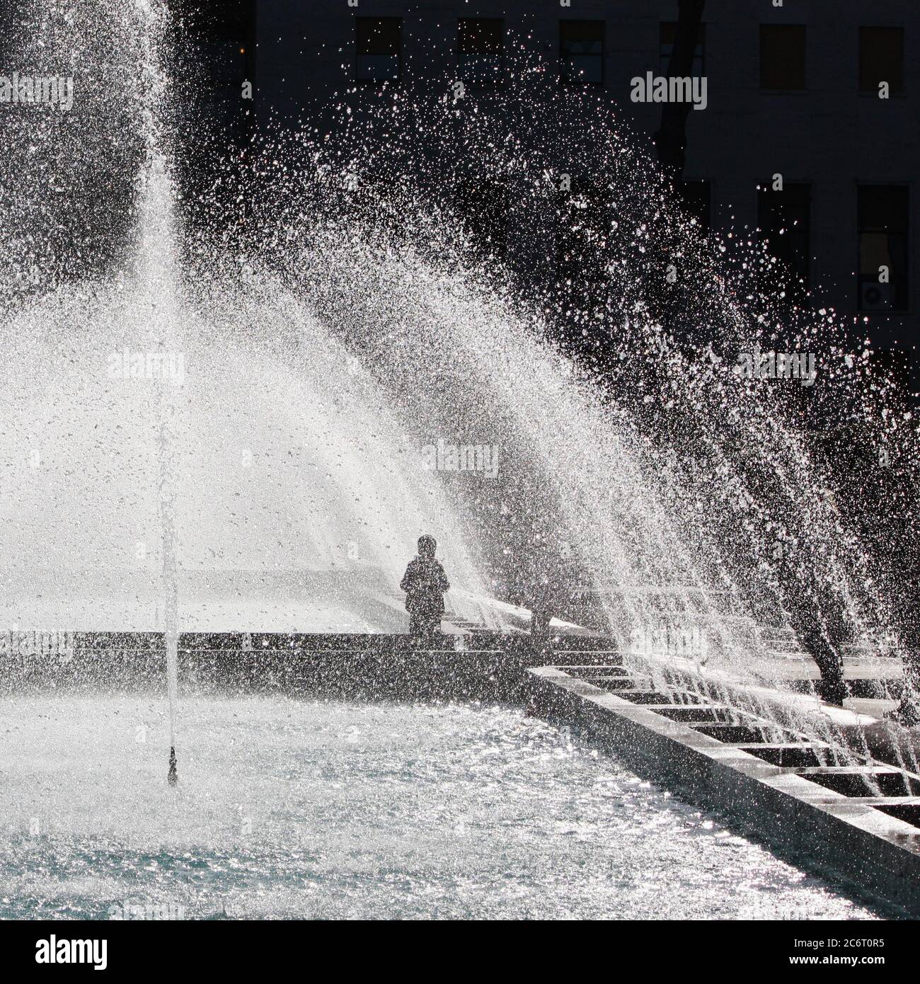 Fountain waterflow splashing drops with kid silhouette Stock Photo - Alamy