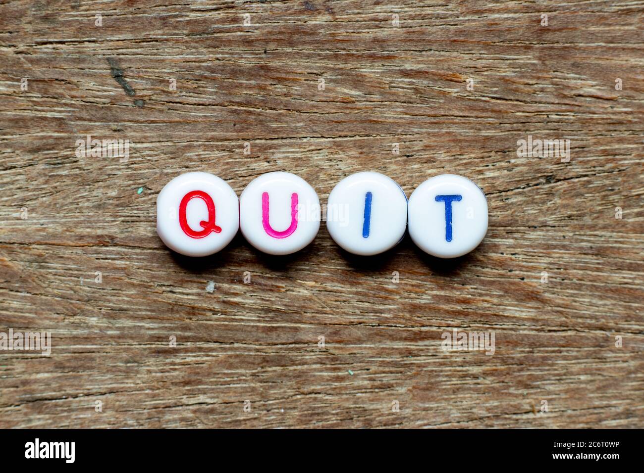 White bead with color letter in word quit on wood background Stock ...