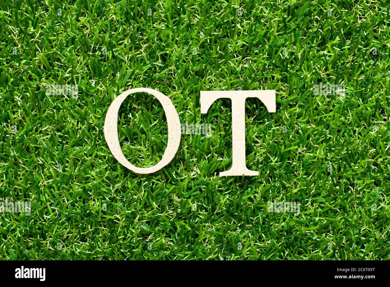 Wood alphabet letter in word ot (abbreviation for overtime) on green ...
