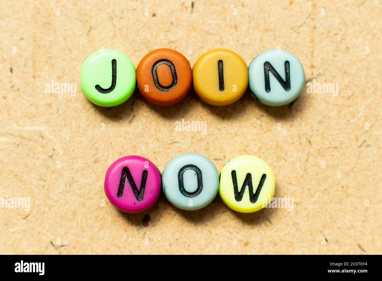 Round color bead with black letter in word join now on wood background ...