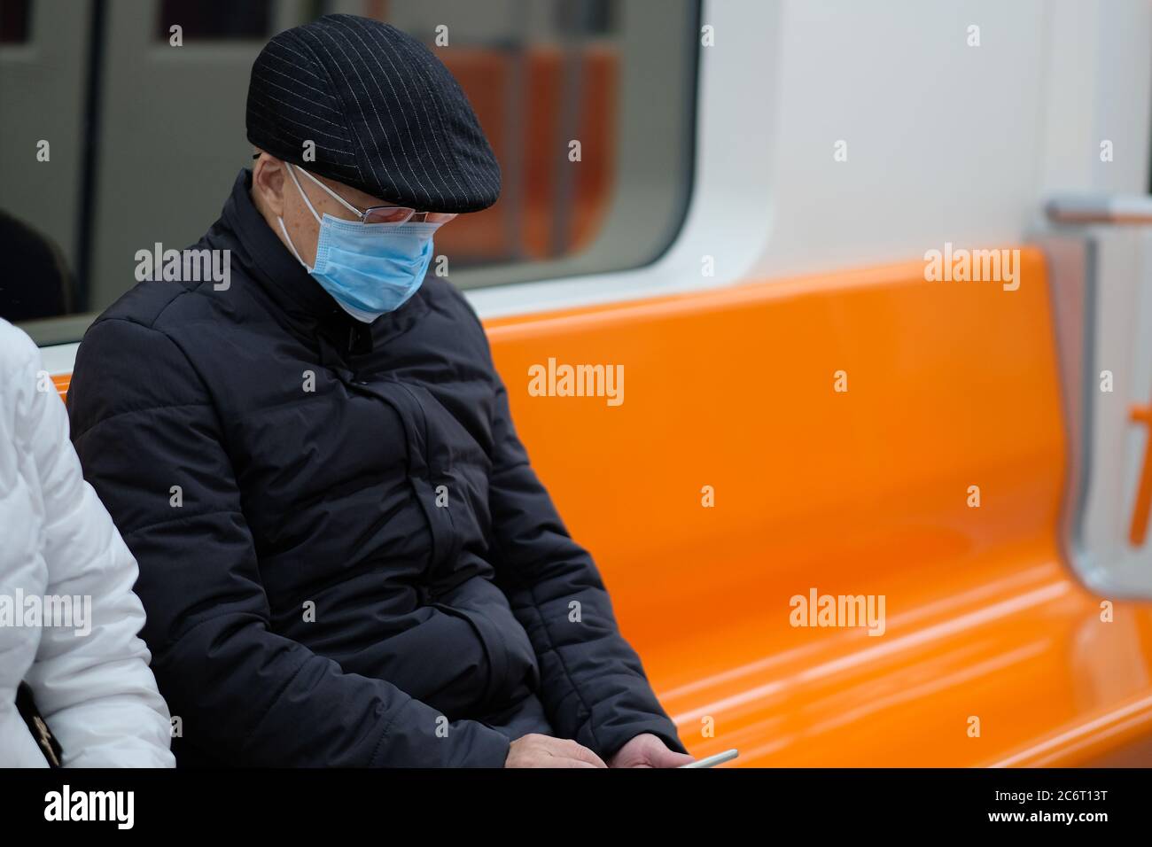 Senior citizen wearing surgical mask sitting in subway in Shanghai ...