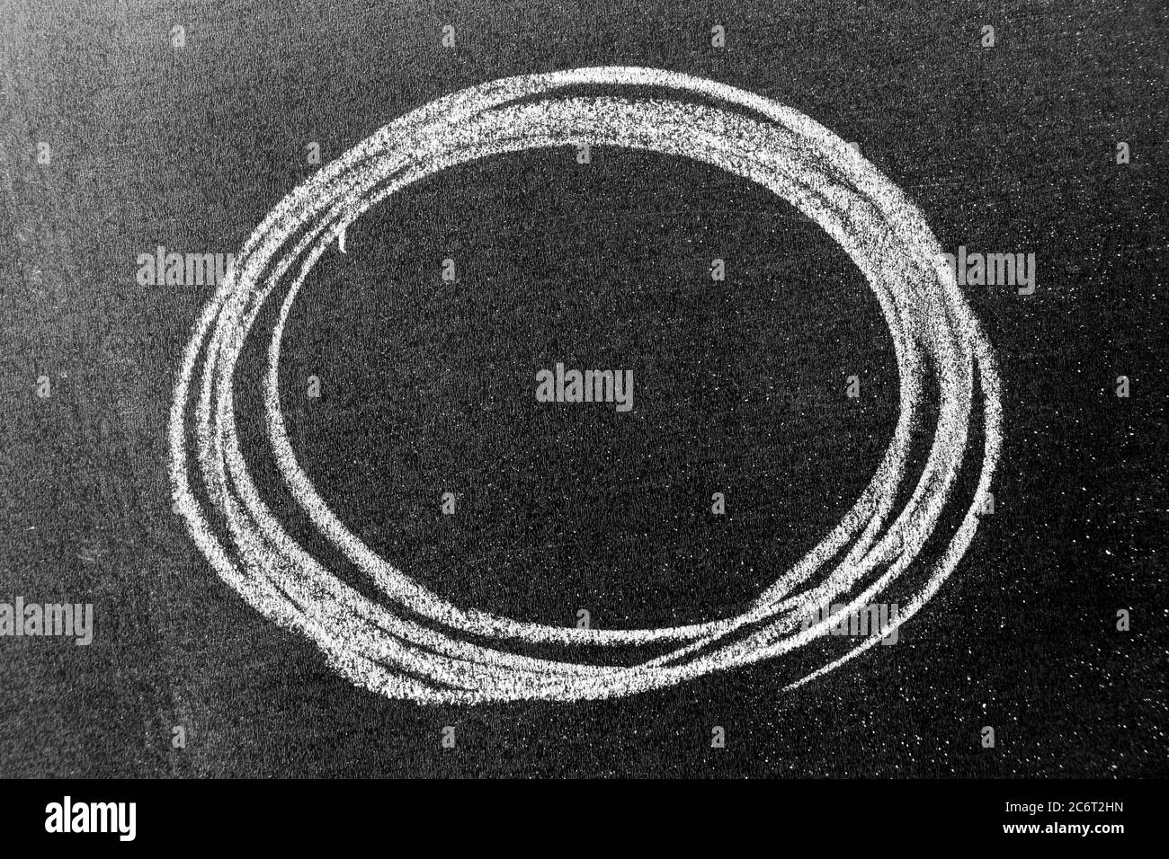 White color chalk hand drawing in circle or oval shape on black board ...