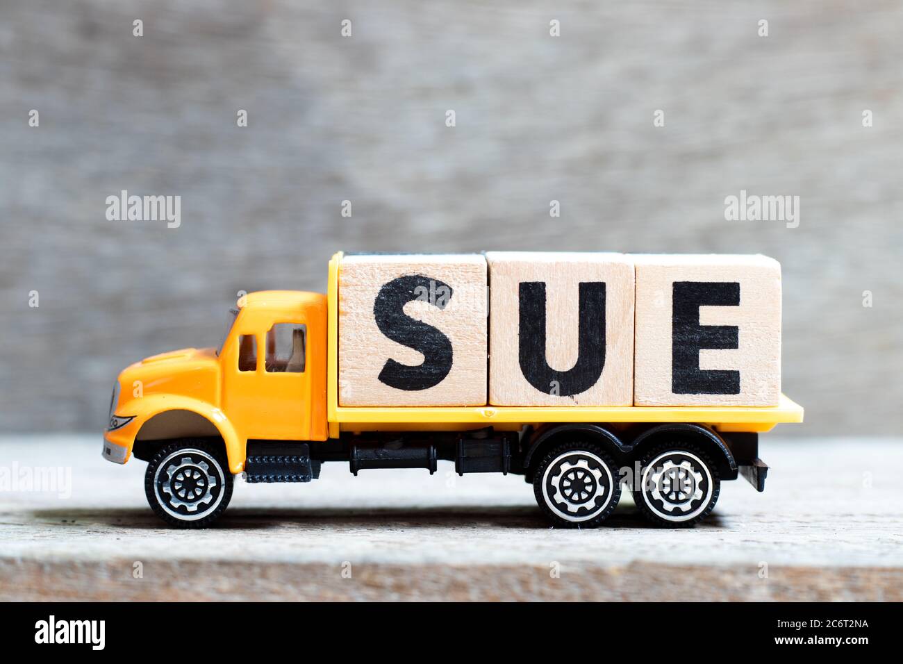 Truck hold letter block in word sue on wood background Stock Photo - Alamy