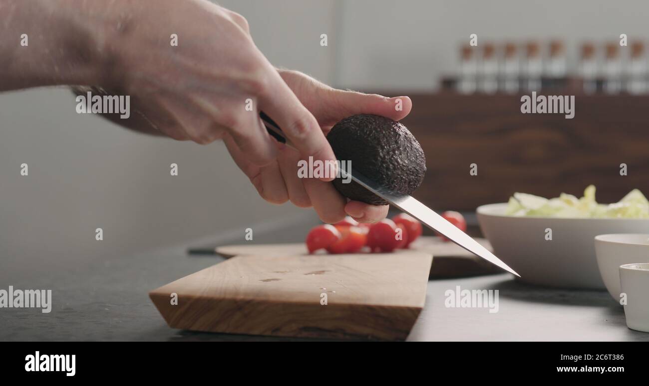 man cutting and open avocado in kitchen Stock Photo - Alamy