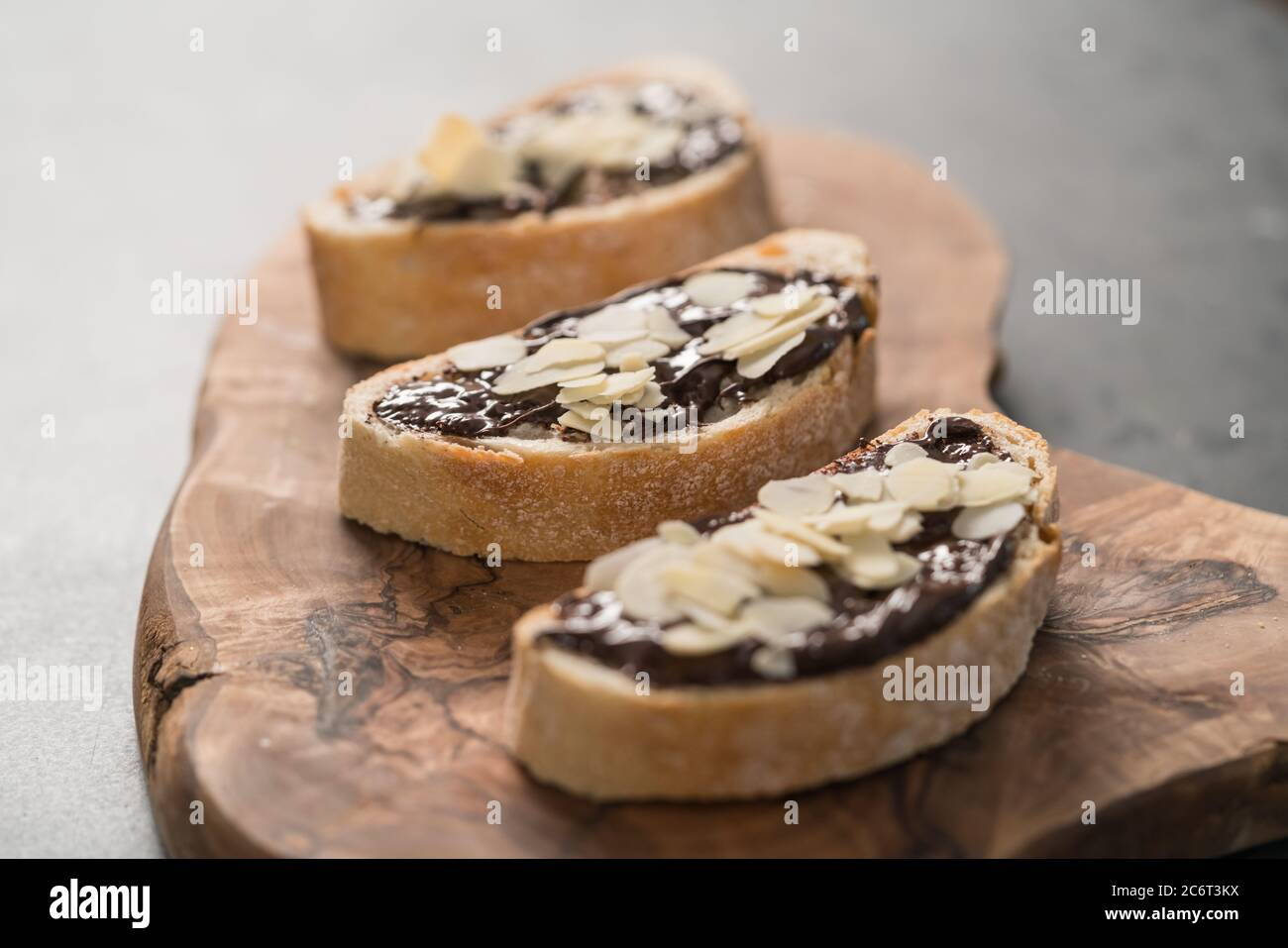 Rustic ciabatta with organic chocolate cream and almond flakes on olive ...