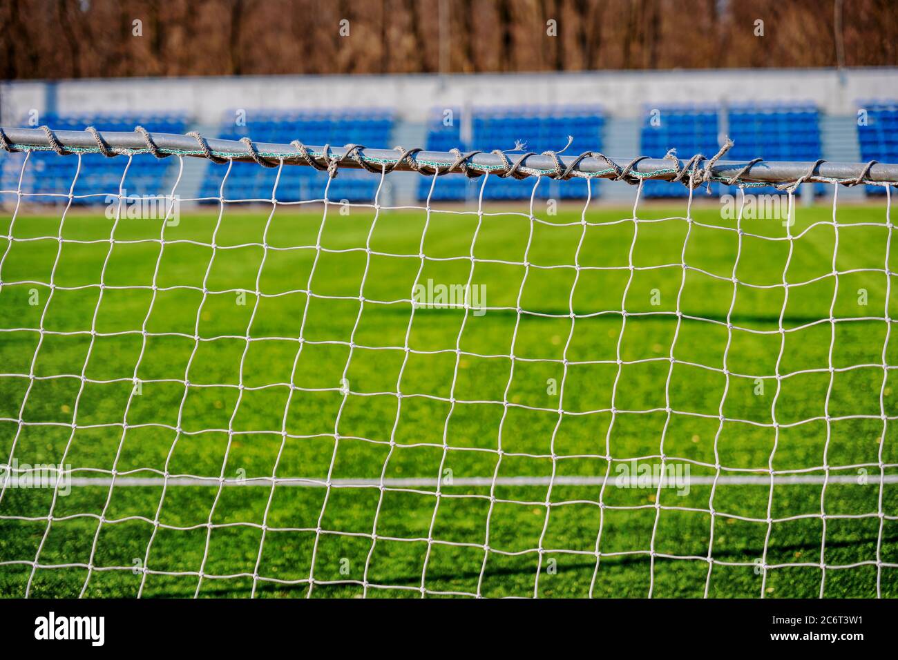 Selective focus on football - soccer goal net against green field and ...