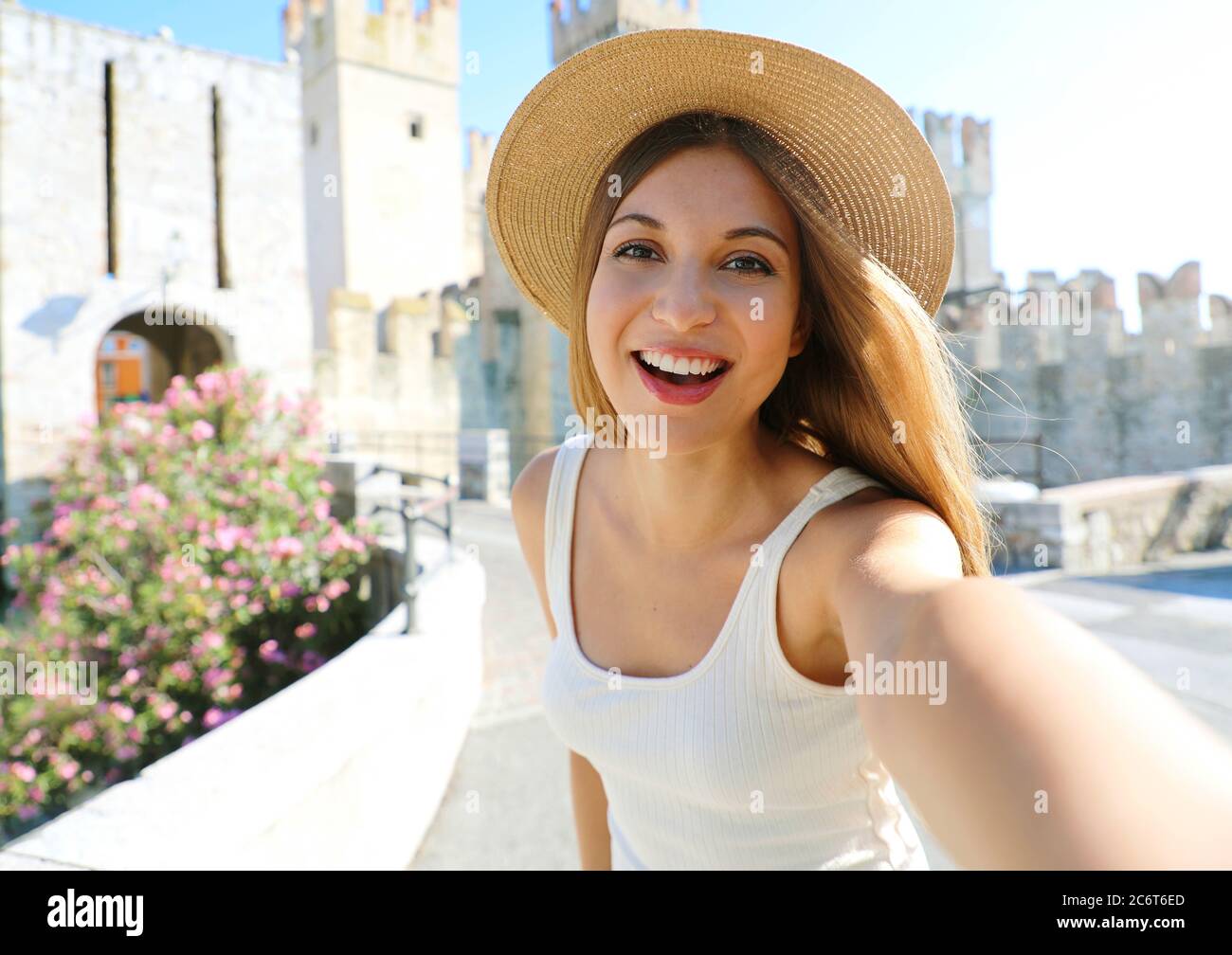 Smiling young tourist woman takes self portrait in Sirmione, Italy ...