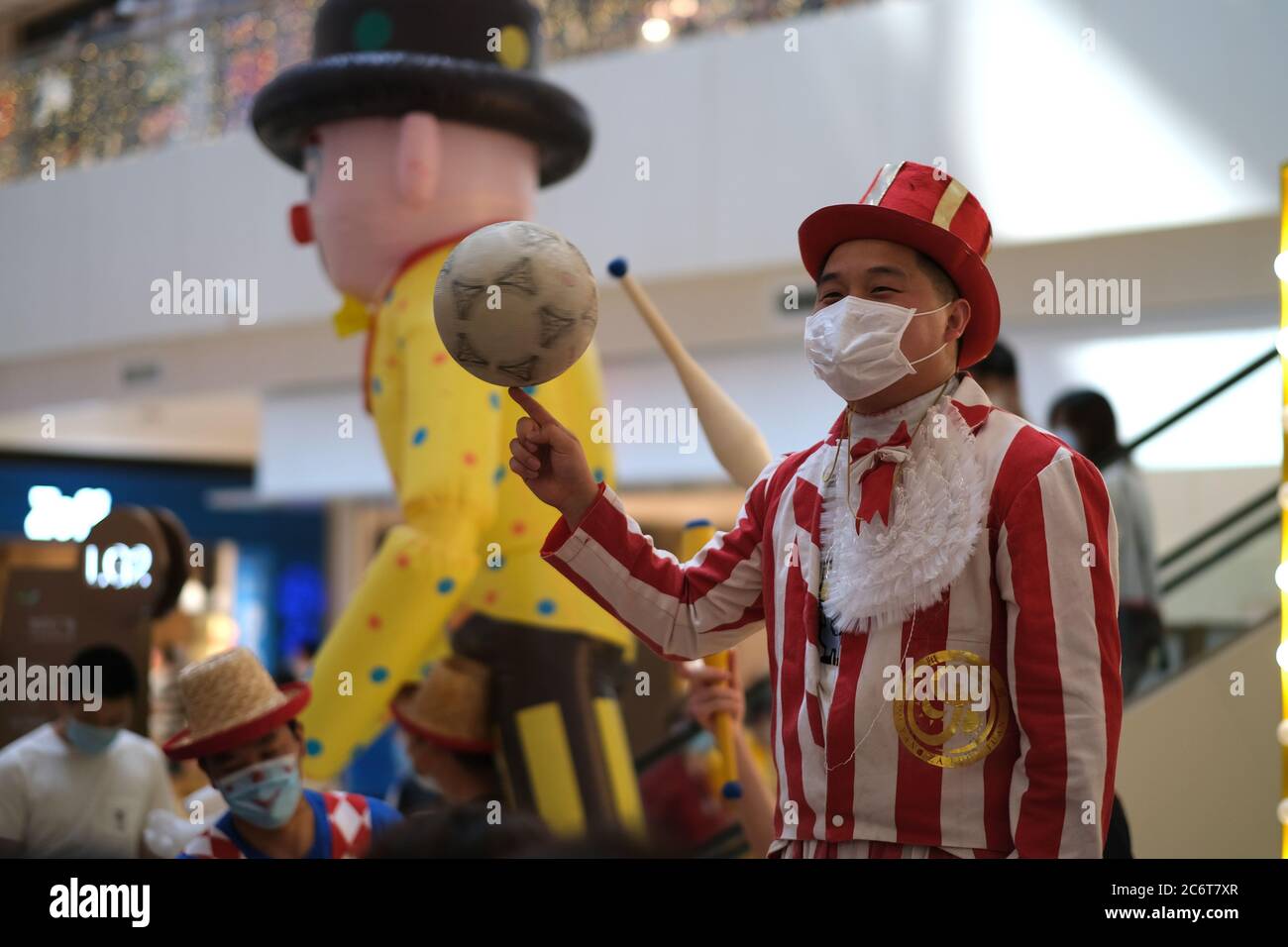 working circus performer in shopping mall, wearing face mask to avoid ...