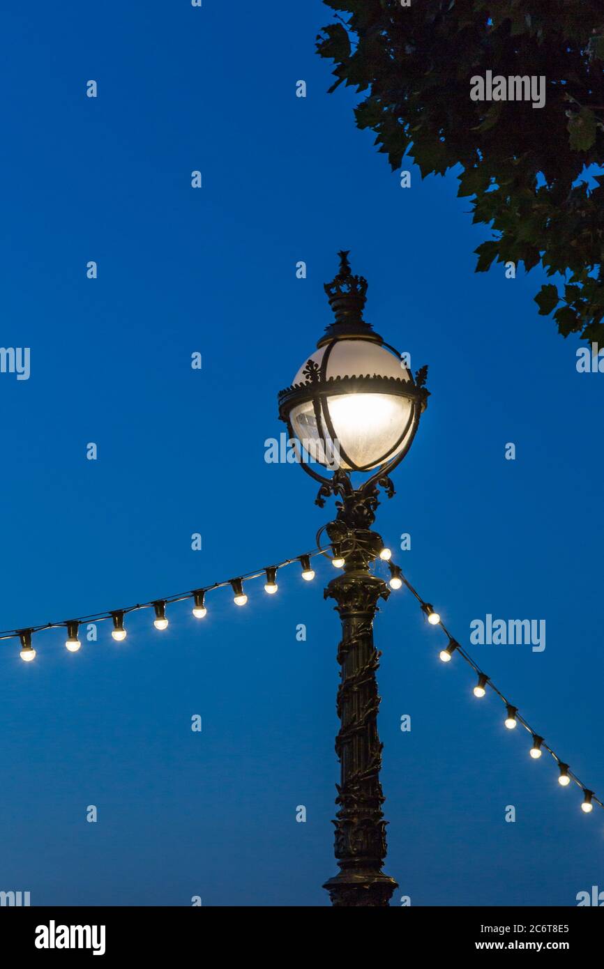 A street lamp and string of lights on the Southbank of the River Thames ...