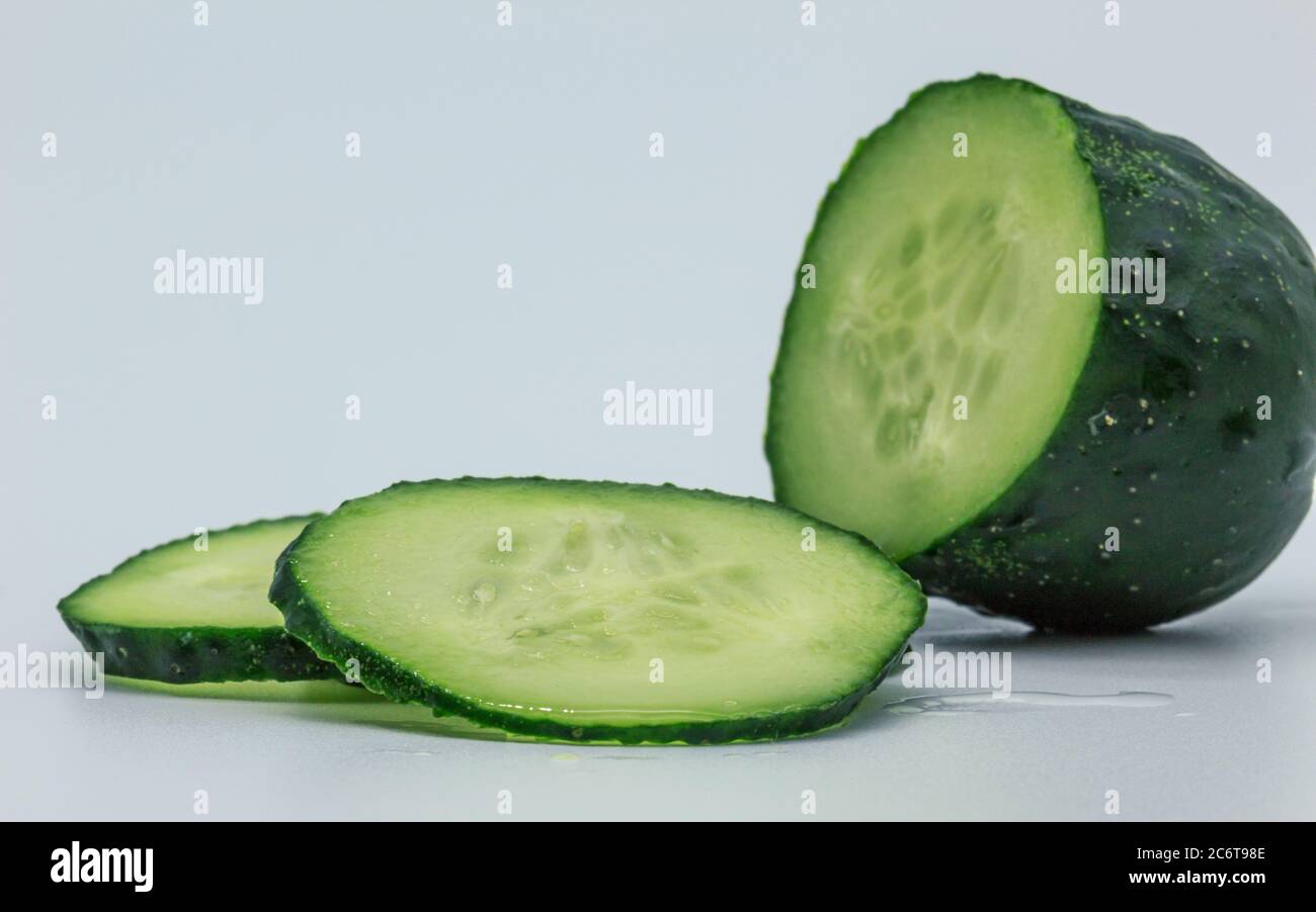 Green wet cucumber half piece of vegetable and two cutted pieces ...