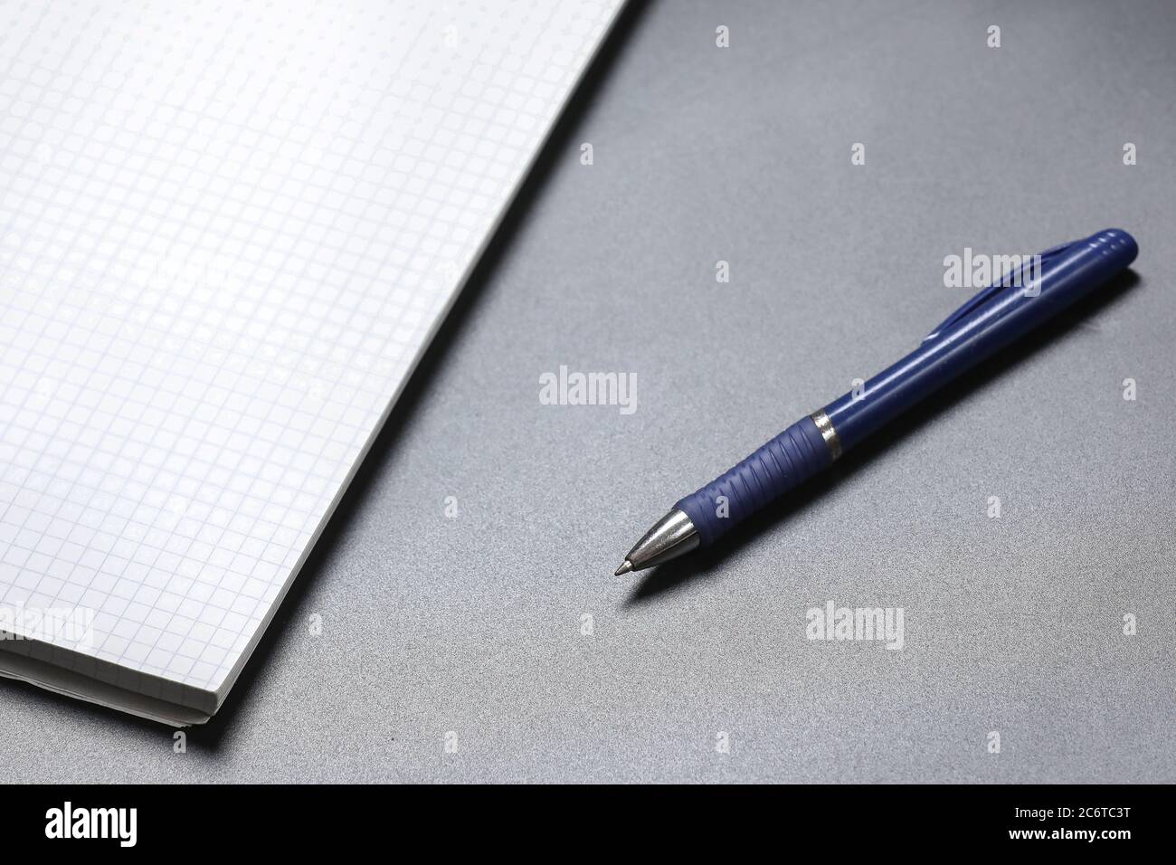 Flat lay view of a white notebook and blue pen on a black table. Copy ...