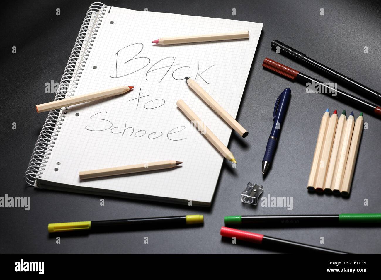 Flat lay view of a white notebook , color pencils, blue pen on a table ...