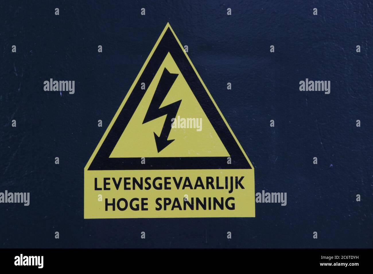 Yellow warning sticker on a door of a transformer house to warn of the ...