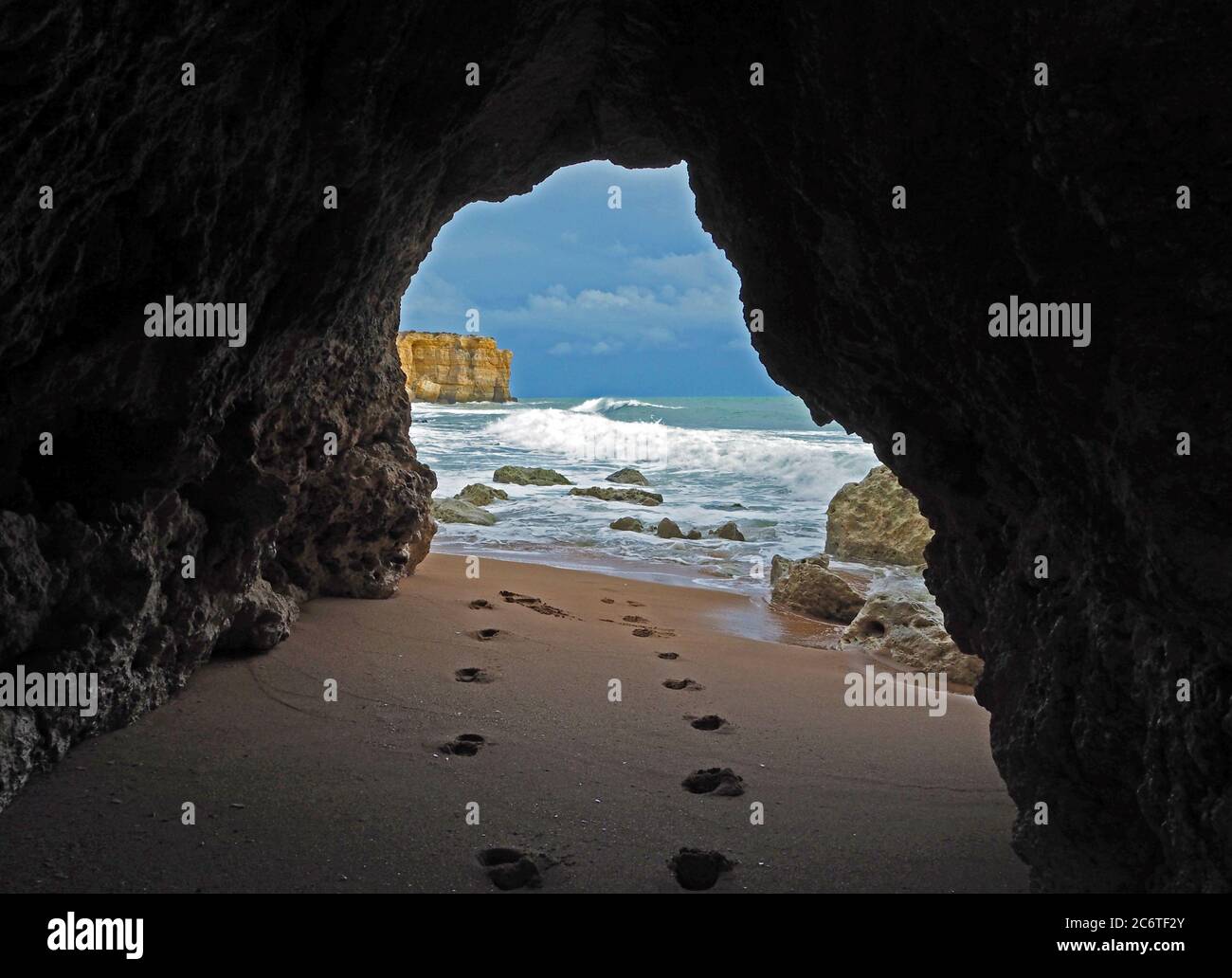 window view on footprints on a sandy beach leading to the blue sea ...