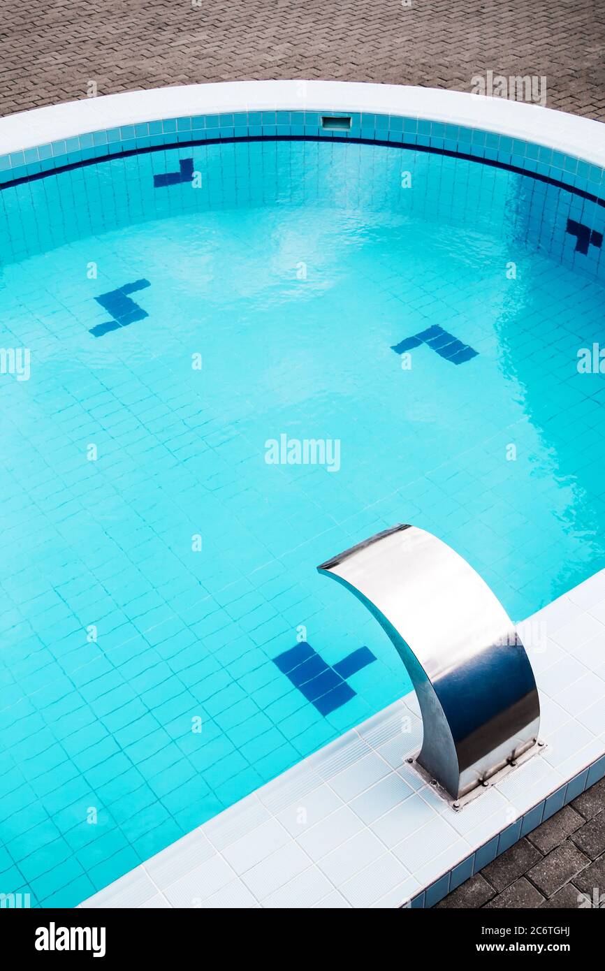 Blue swimming pool with a modern stainless steel water flowon massage ...