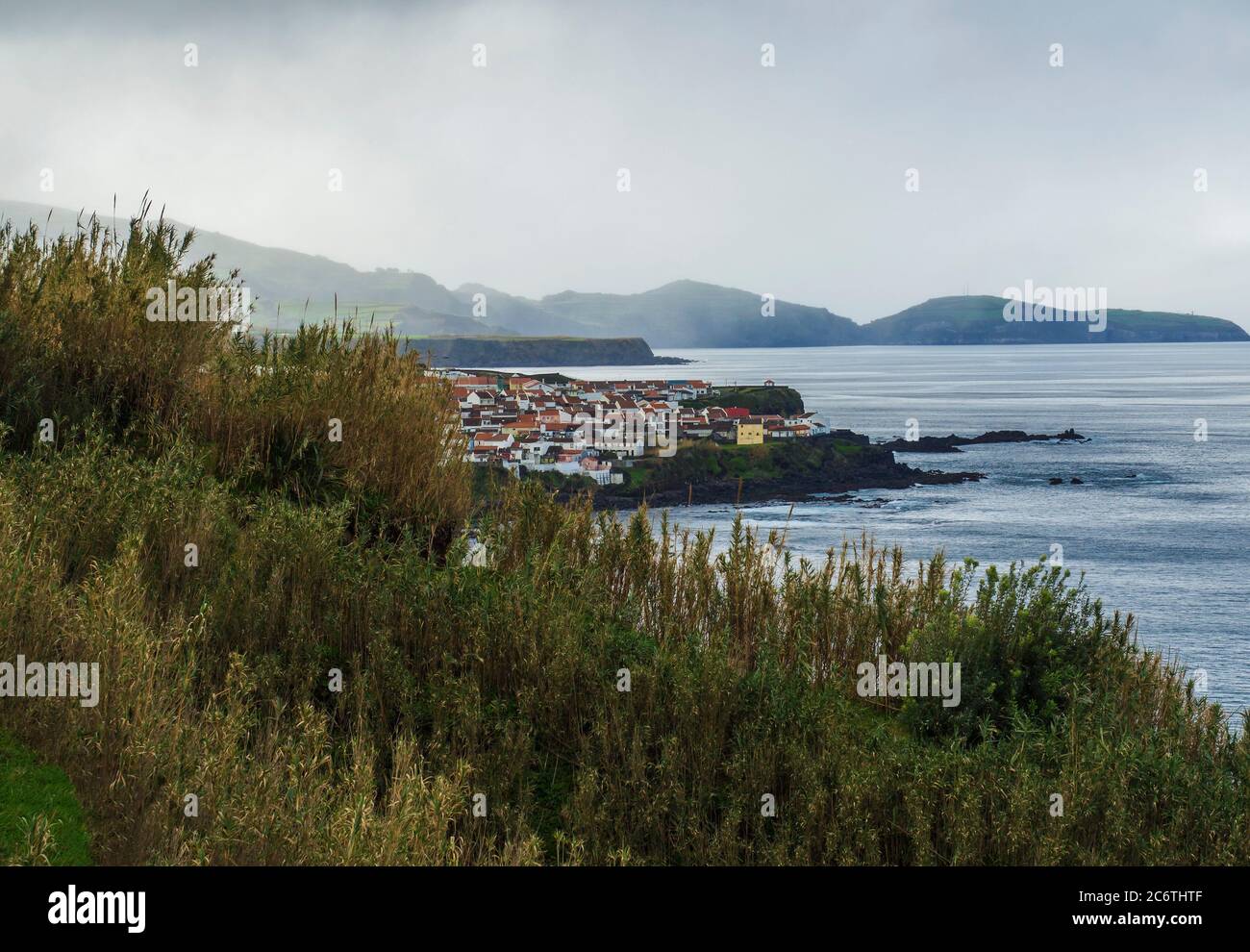 Colorful small coastal village houses on rocky lava shore above ...