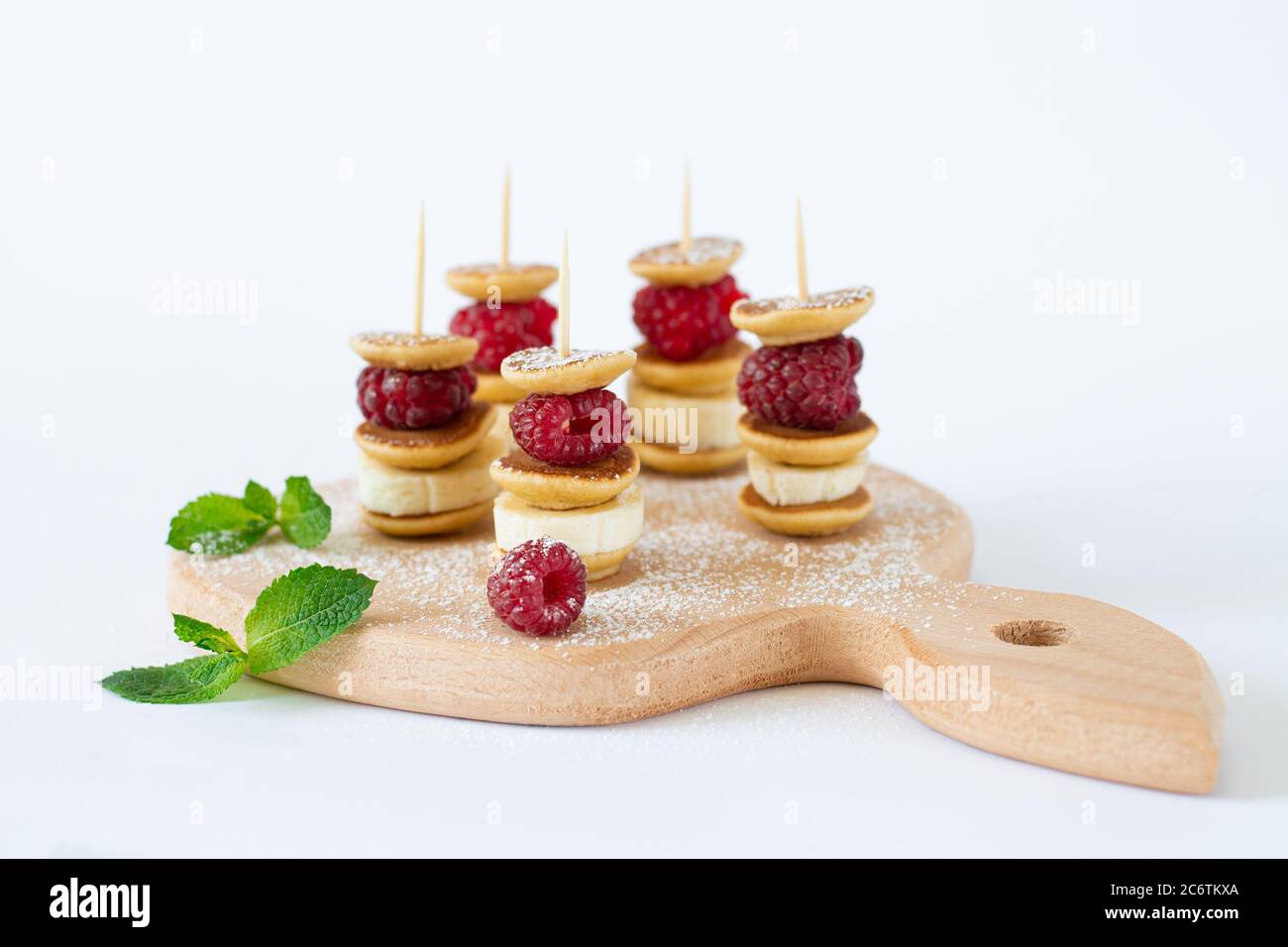 Trendy food - skewers with mini pancakes, raspberry, banana, sugar ...