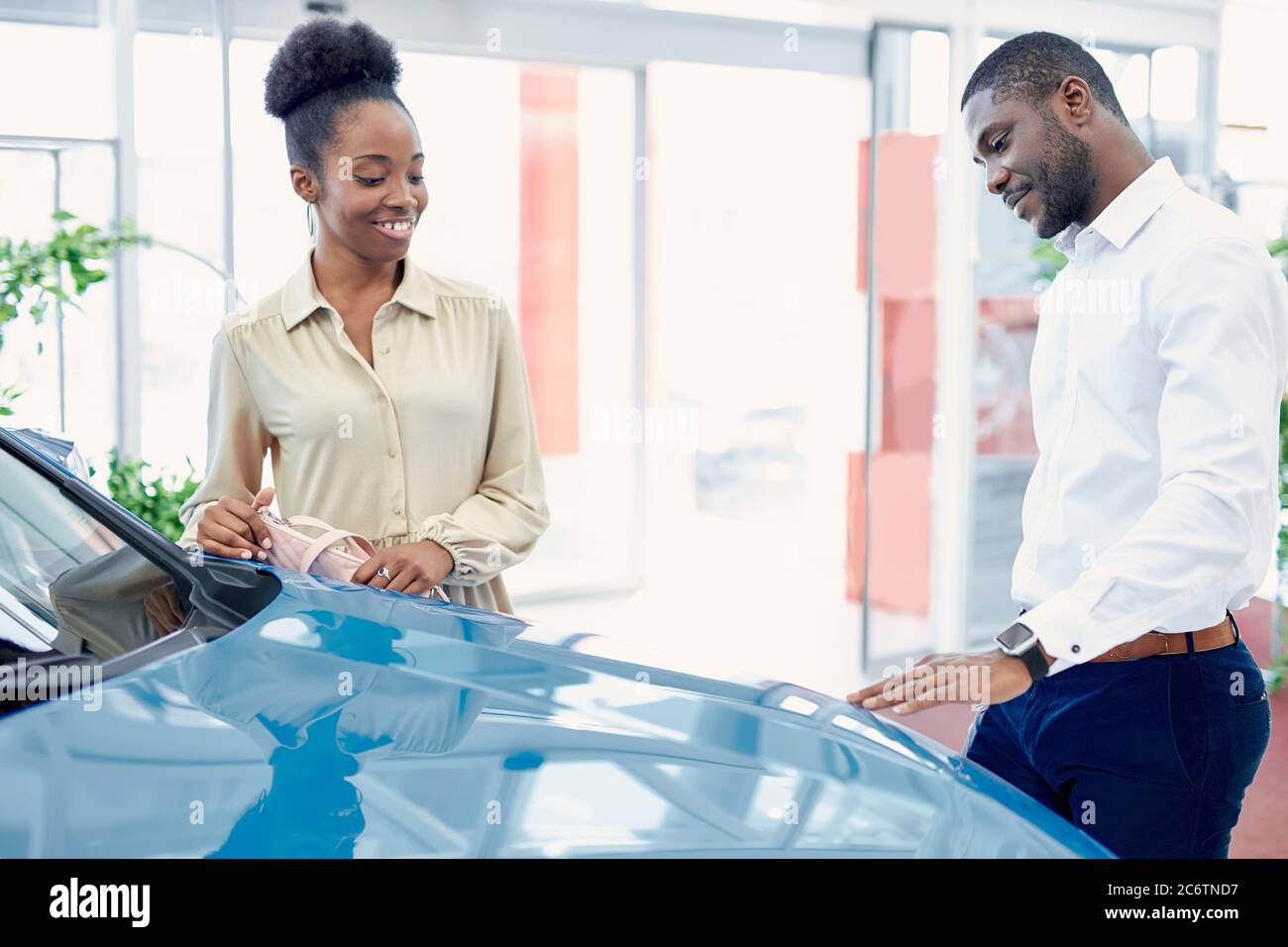 black couple in contemplation before making purchase in cars showroom ...
