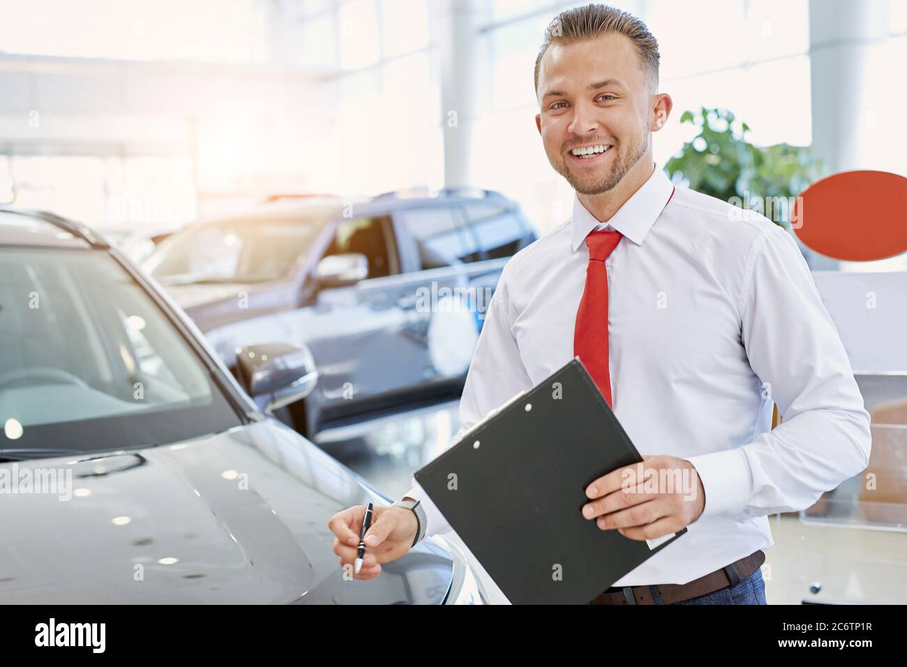 portrait of open-minded professional salesman in cars showroom ...