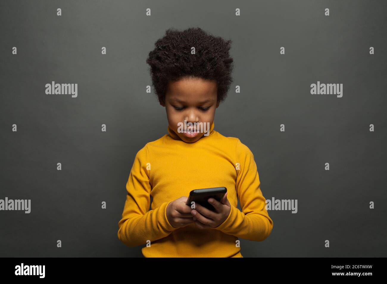 Little black child boy using smartphone on black background Stock Photo ...