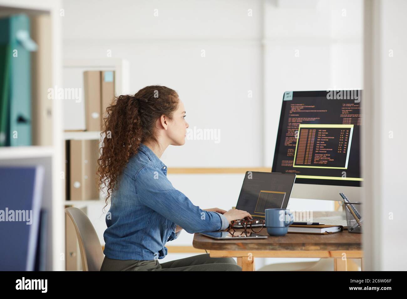 Side view portrait of female IT developer using computer while coding ...
