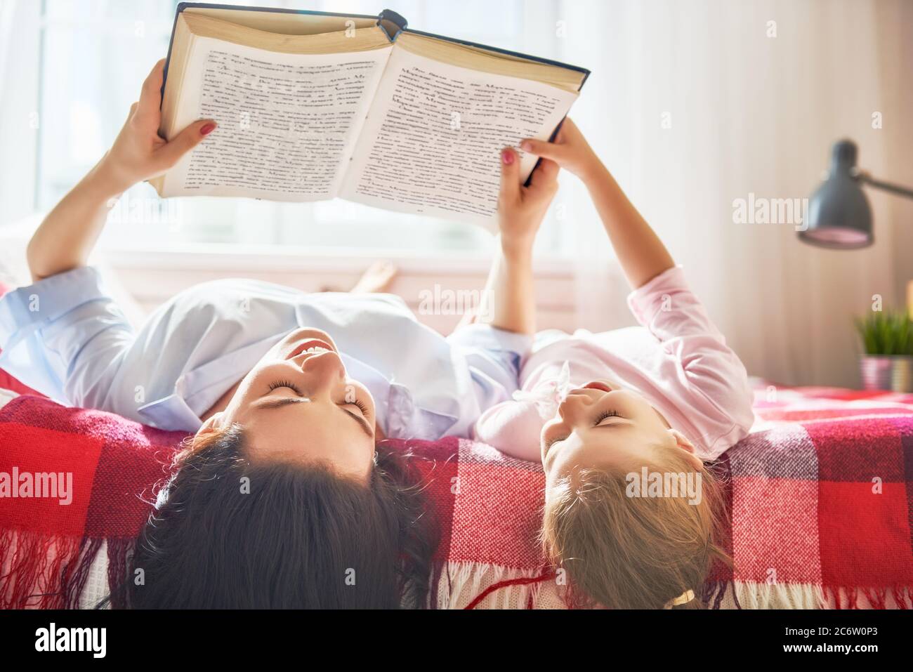 Pretty young mother reading a book to her daughter. Family holiday and ...