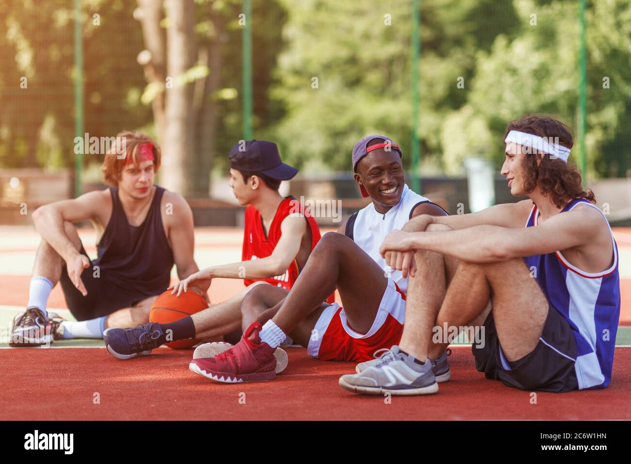 Multiracial basketball team taking break after their game at outdoor ...