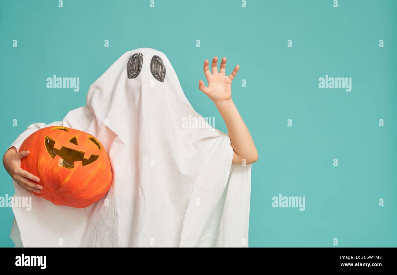 Happy Halloween! Cute little kid in ghost costume on teal background ...