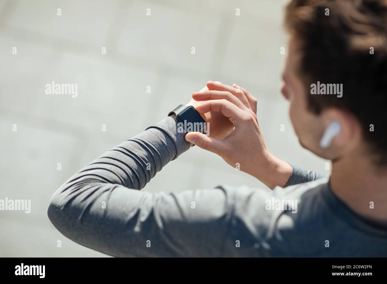 Modern run with handy gadgets. Guy in wireless headphones, stops and ...