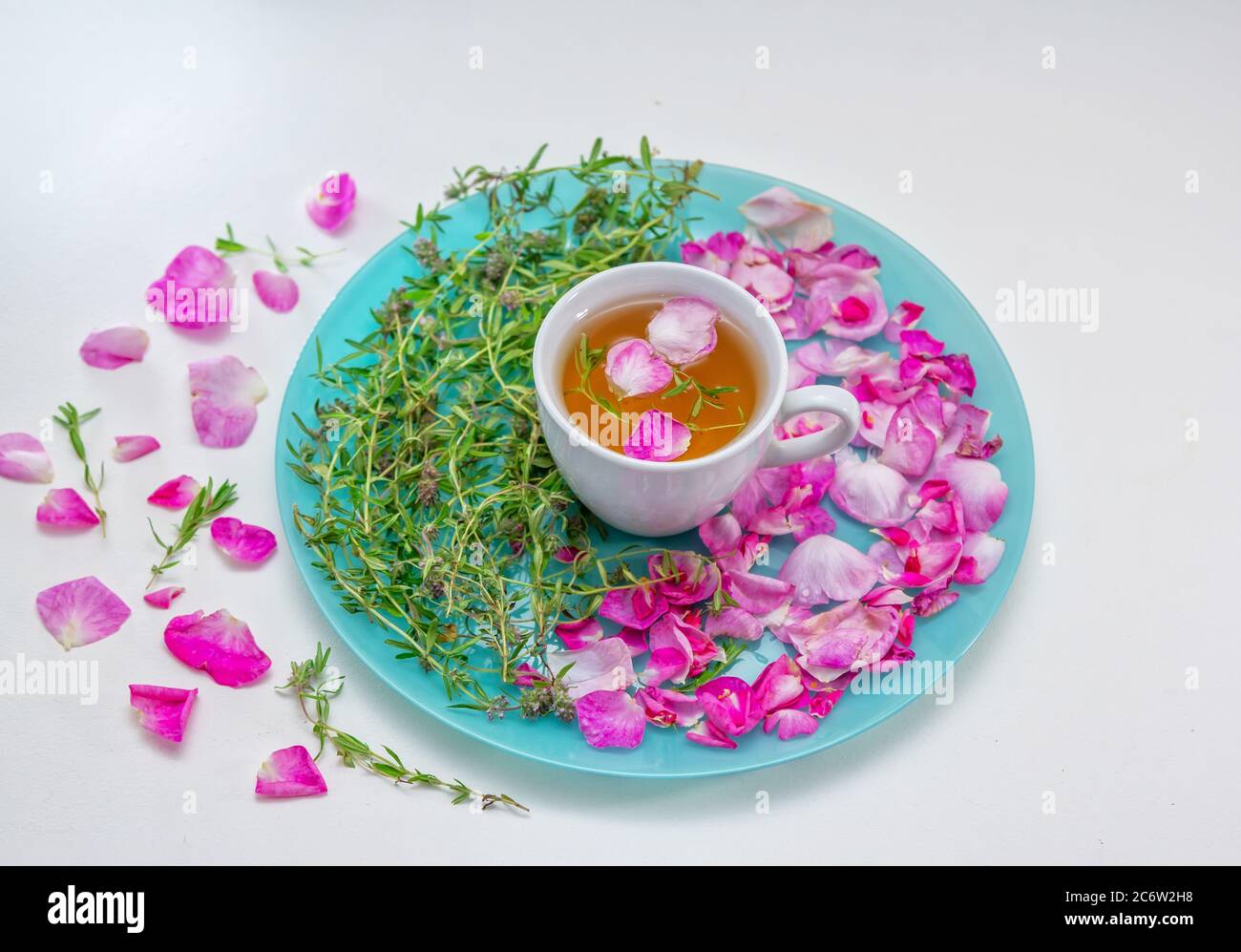 Homemade herbal tea in a white cup. Tea rose petals and thyme on a ...