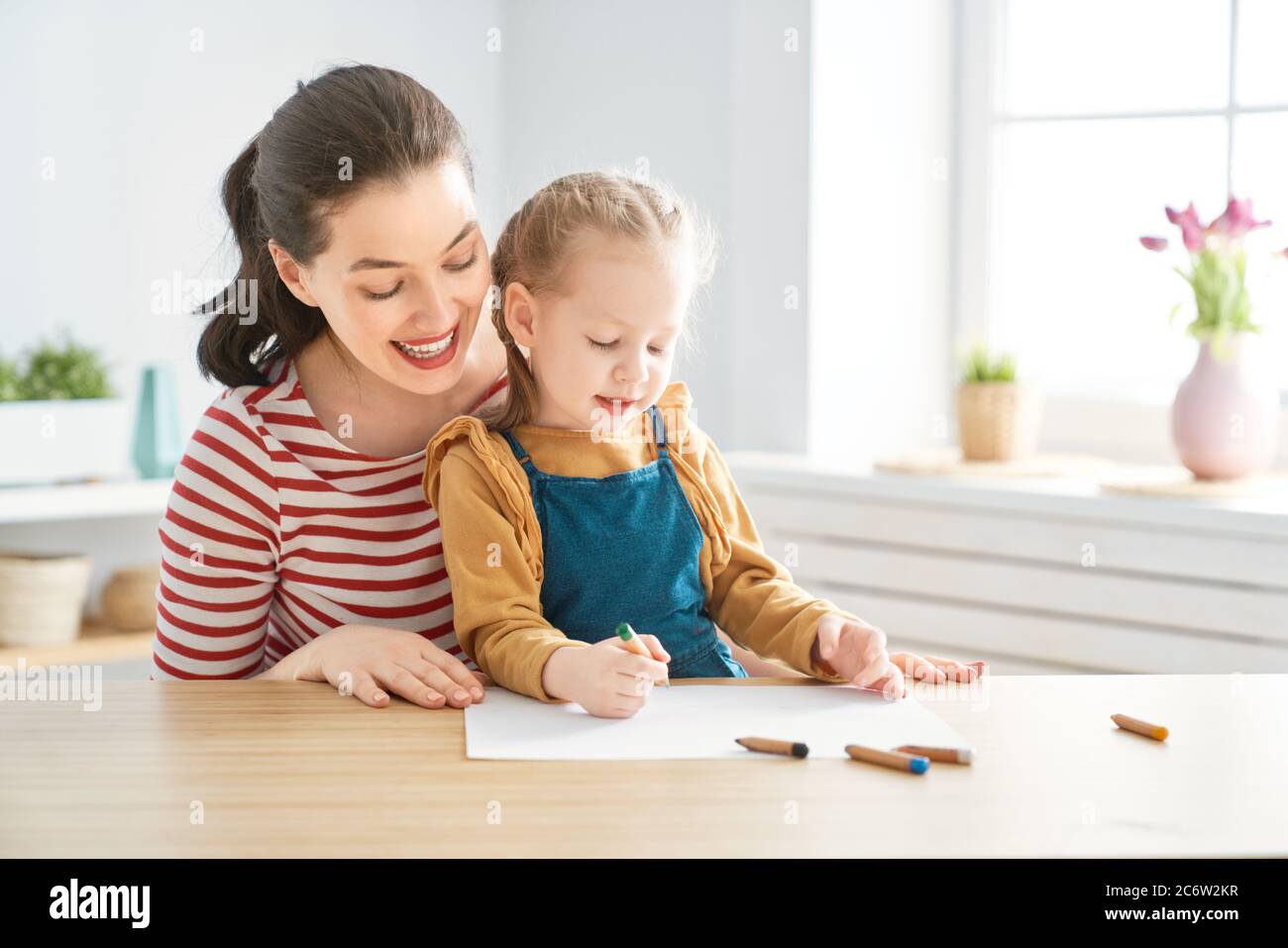 Happy family. Mother and daughter drawing together. Adult woman helping ...