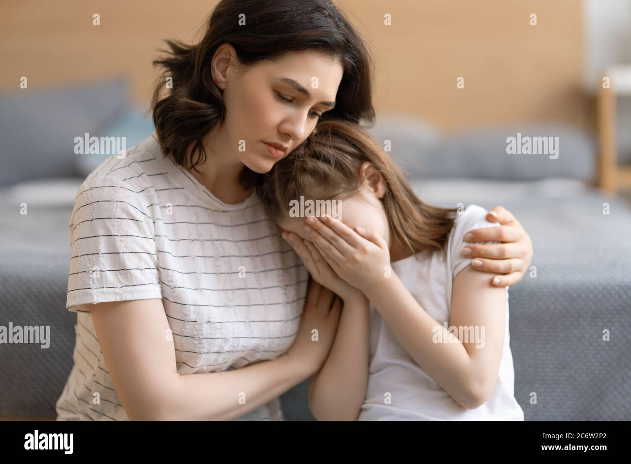 Mother is feeling sorry for a crying child. Mum is hugging her daughter ...