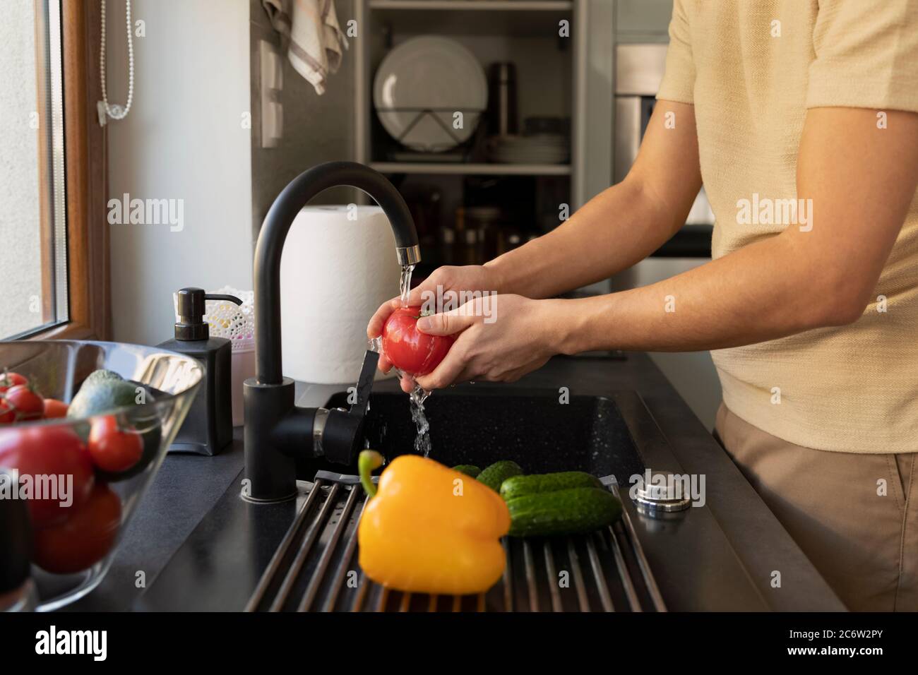 A man washes vegetables in the kitchen sink Stock Photo - Alamy
