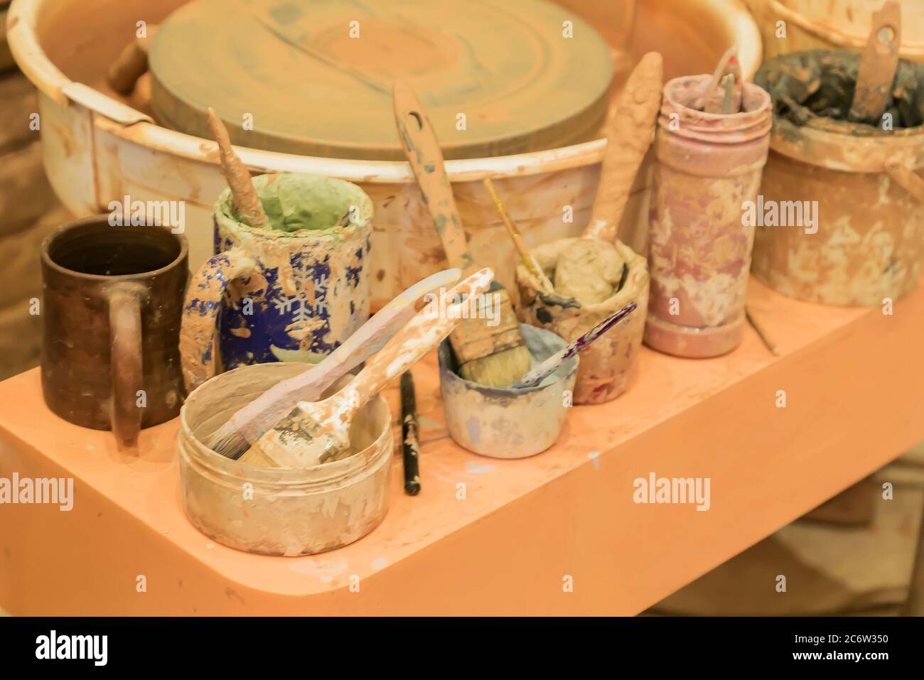 close up of dirty pottery wheel and colorful mud in jars after work ...