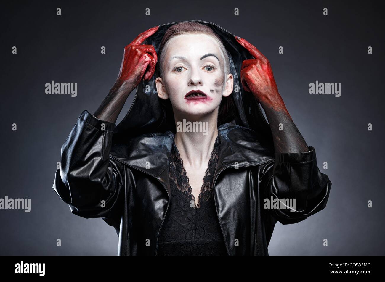 Woman in black leather raincoat taking off hood Stock Photo - Alamy