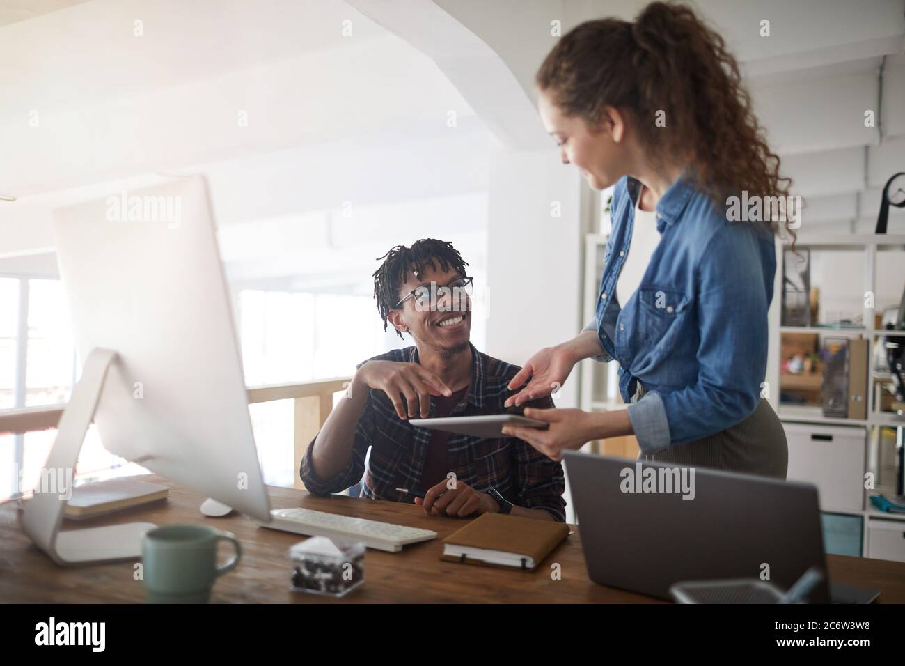 Portrait of female IT developer talking to smiling African-American ...