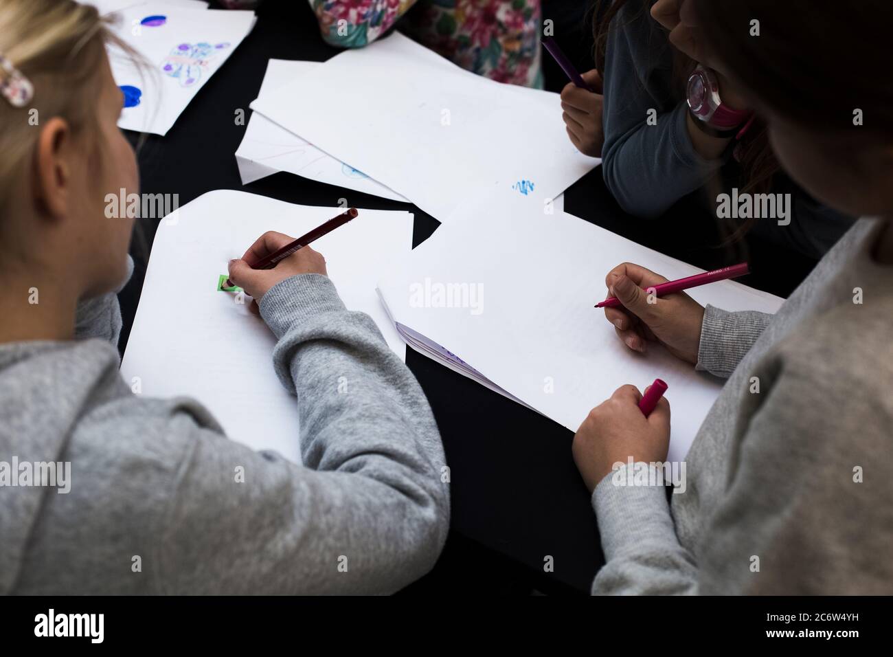 Two school girls writing on empty sheets of paper Stock Photo - Alamy